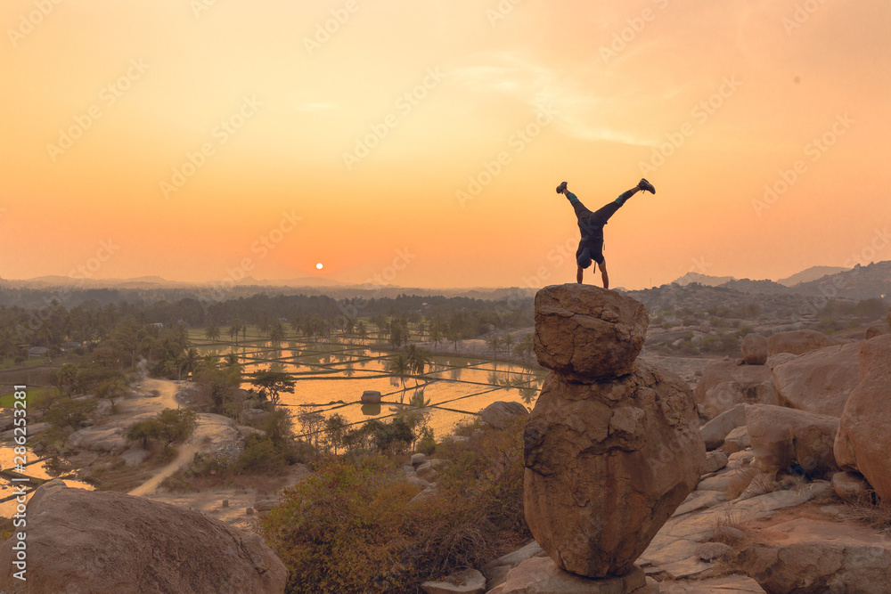 An Acrobat performs a hand stand at the spectacular sunset point at ...