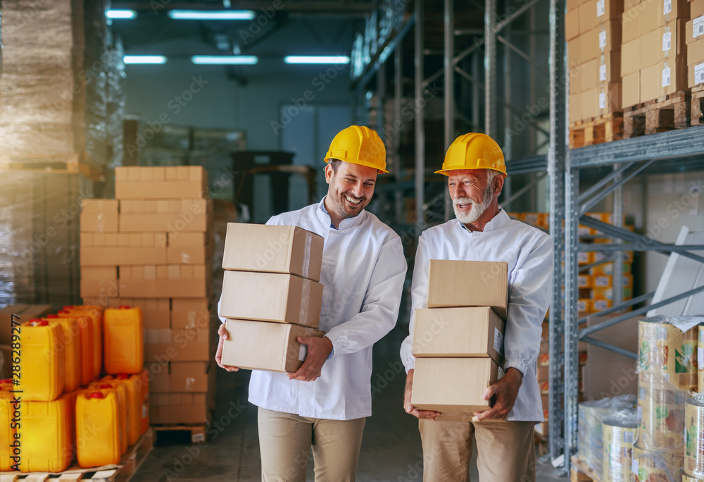 Three quarter length of two smiling Caucasian storage employees in ...