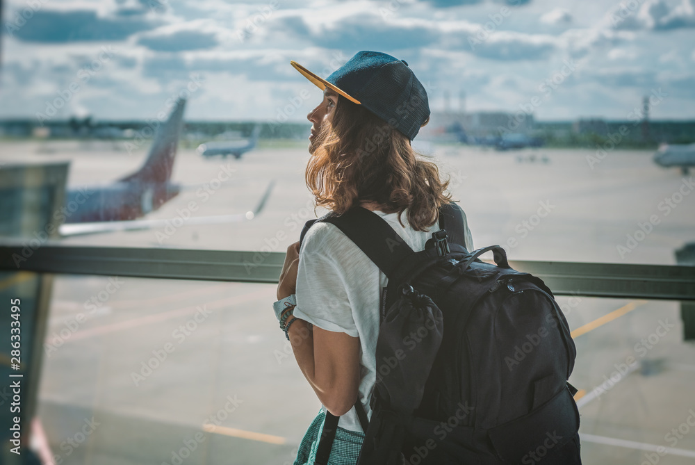young girl traveler with backpack at the airport on the background of ...