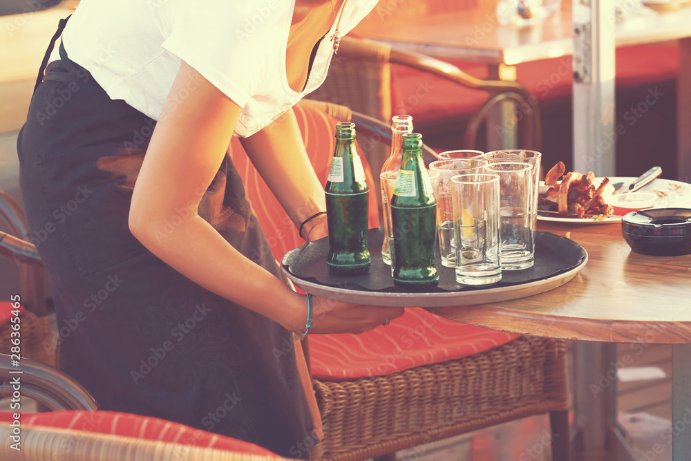 Waitress is holding a tray with dirty dishes and leftover food ...