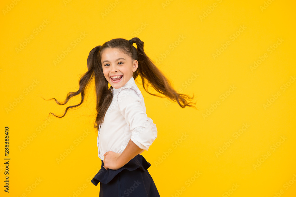Looking happy. Happy little girl smiling in school uniform on orange ...