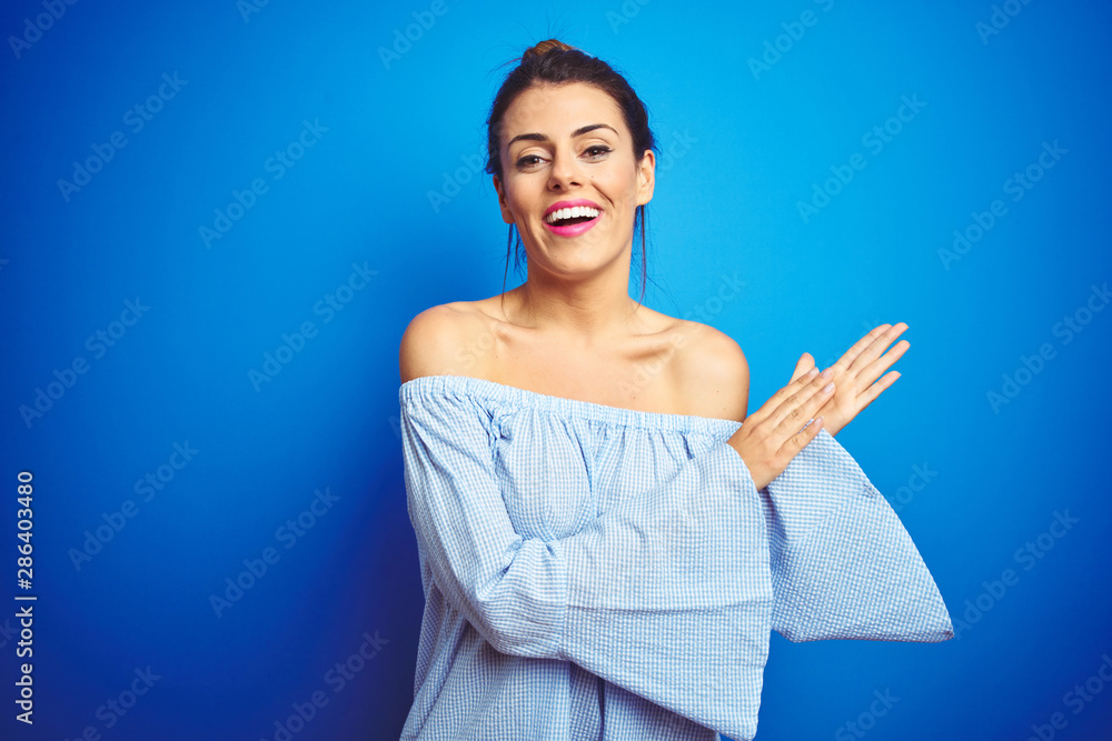 Young beautiful woman wearing bun hairstyle over blue isolated ...