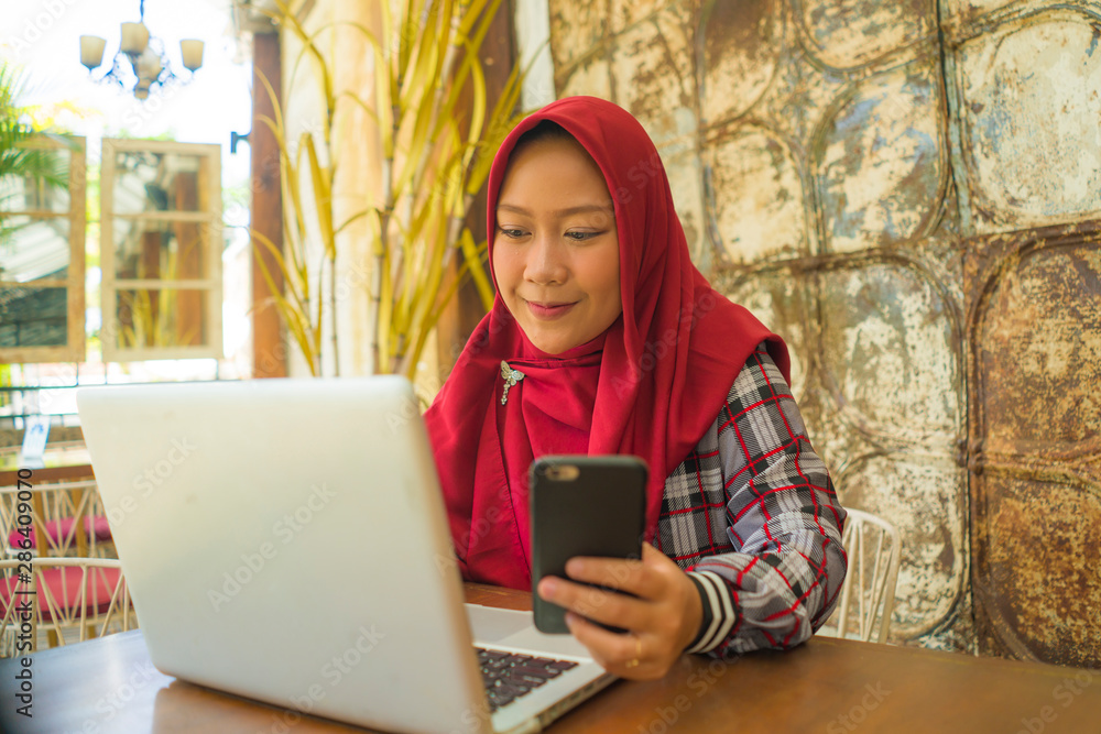 Muslim student girl in hijab networking with laptop . Young happy and ...