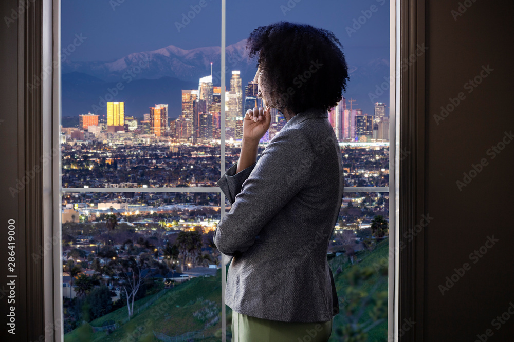 Black female business woman looking out the window of an office in Los ...