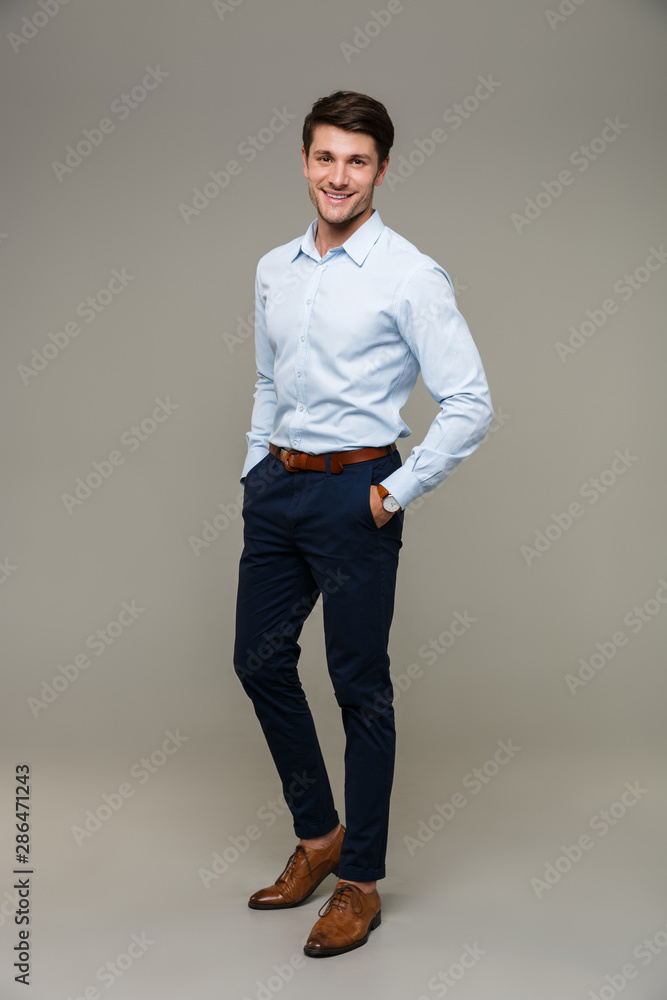 Image of happy young man wearing formal clothes smiling at camera with ...