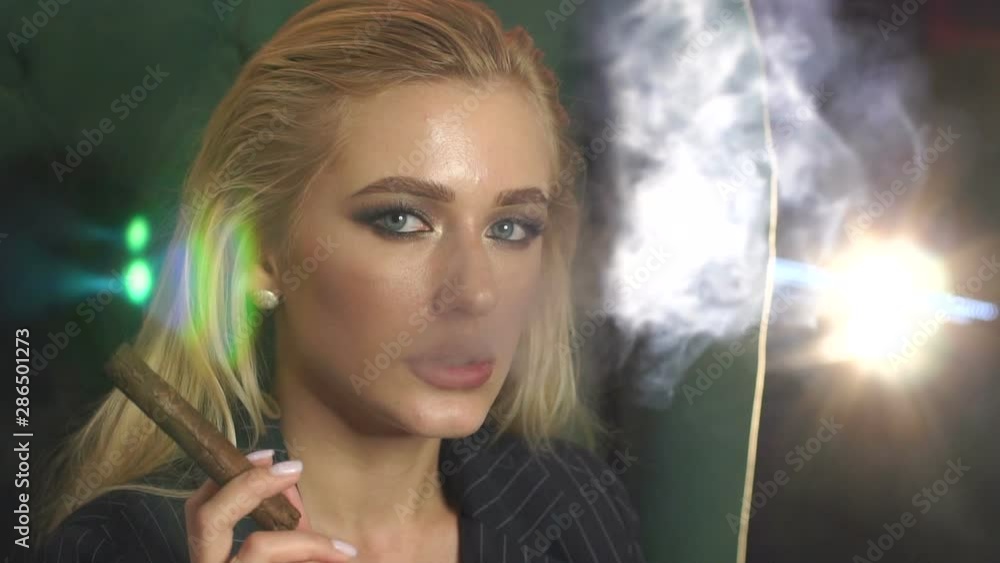 A successful business woman smokes a cigar in an expensive luxury bar ...
