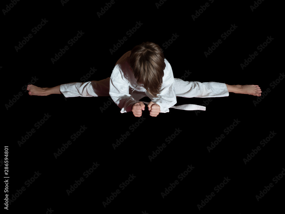 The karate kid, dressed in karate gi, exercises flexibility, performs ...