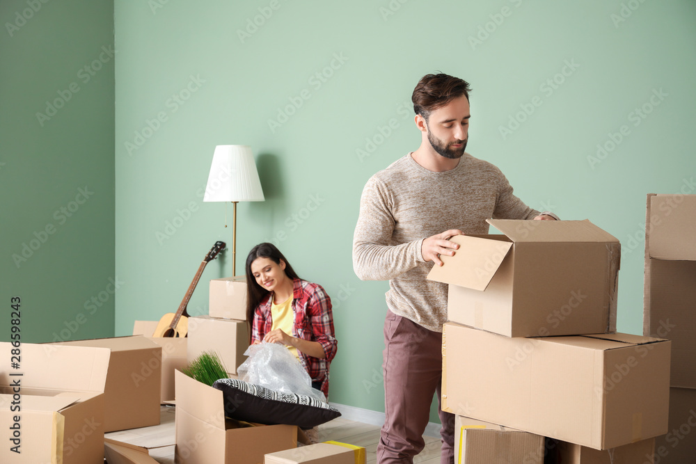 Young couple unpacking things after moving into new house Stock Photo ...