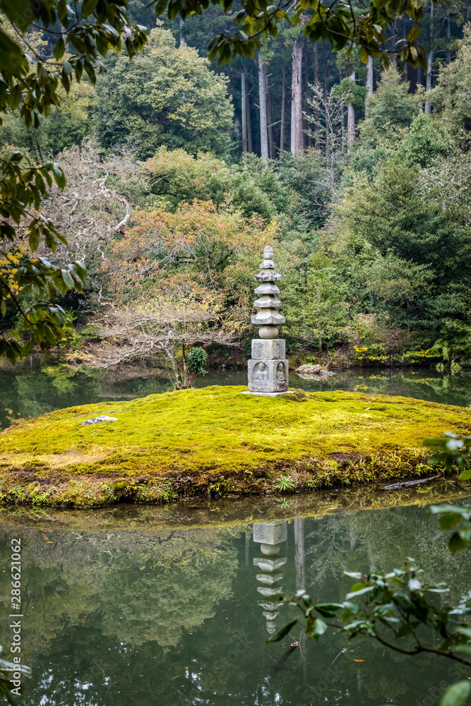 Small stone sculpture sits on a mossy island and reflects perfectly in ...