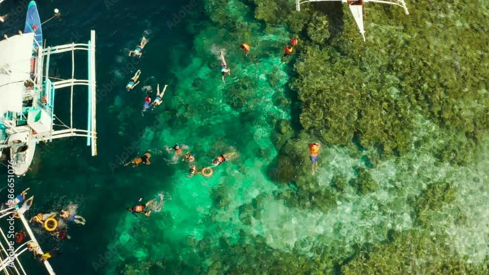 People snorkeling over coral reef with clear blue ocean water, top view ...
