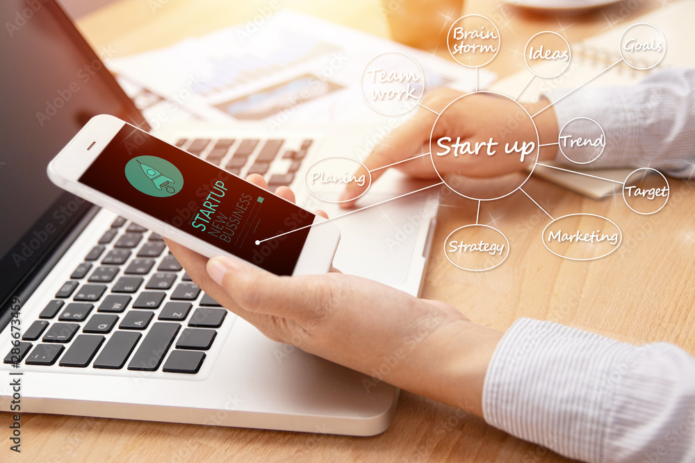 people using smart phone with startup business and rocket logo on ...