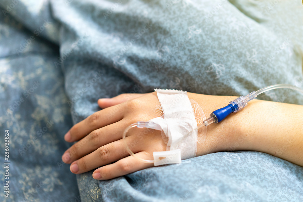 Focus on the hand of a patient in hospital ward on bed during dosing of ...