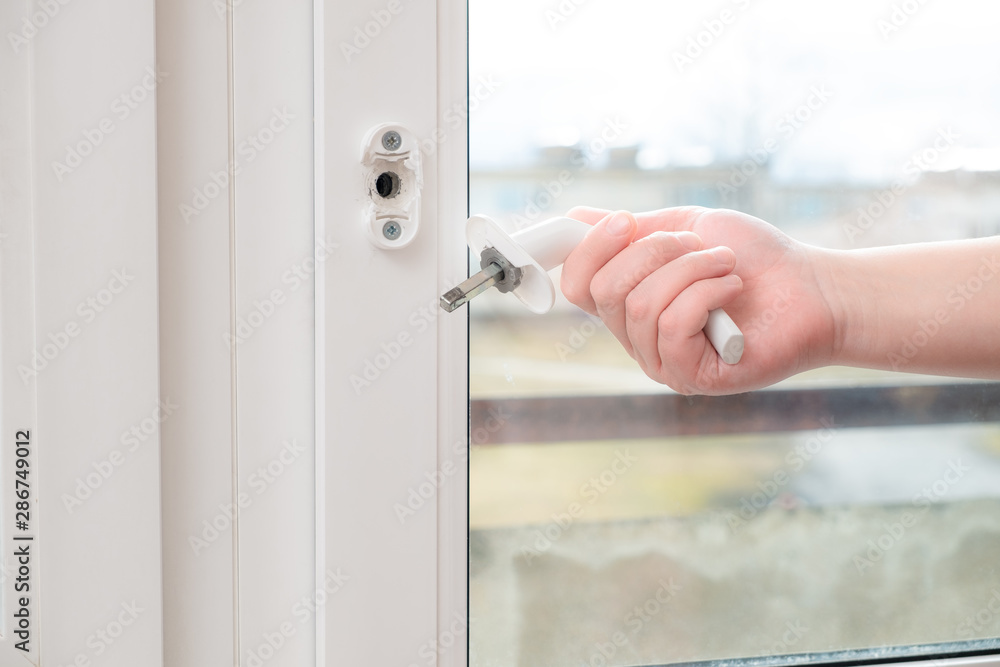 A man holds in his hand a broken doorknob. The door is closed due to ...