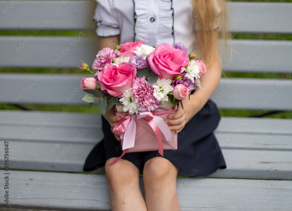 School girl dressed in school uniform holding a bright pink festive ...