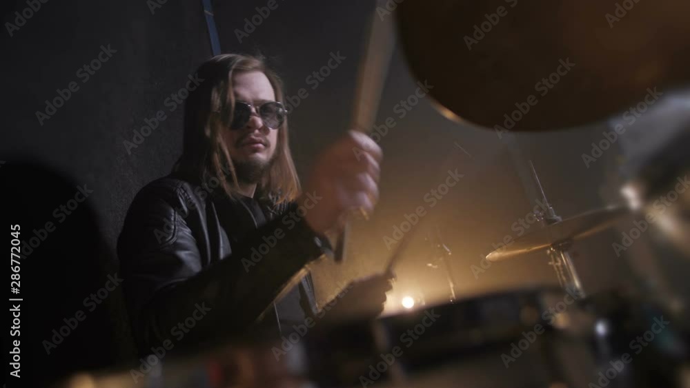 Side view of stylish rock musician with drumsticks playing on ...