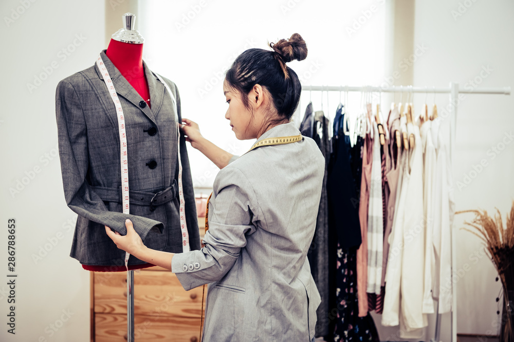 Asian female fashion designer girl making fit on the formal suit ...