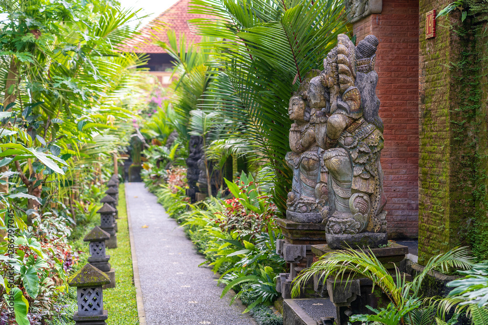 The sidewalk leads to a enter in house with Balinese sculptures in a ...