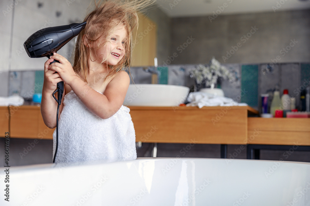 Happy cute girl is drying her hair Stock Photo | Adobe Stock
