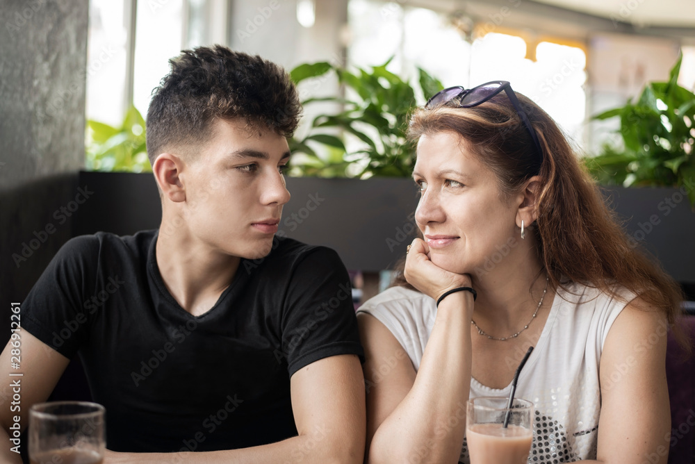Pretty Woman Sitting With Her Teenage Son In A Cafe And Talking Son
