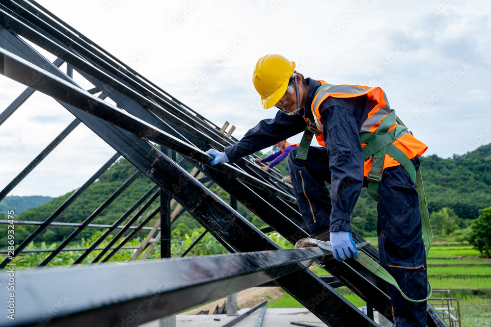 Construction worker wearing safety harness using secondary safety ...