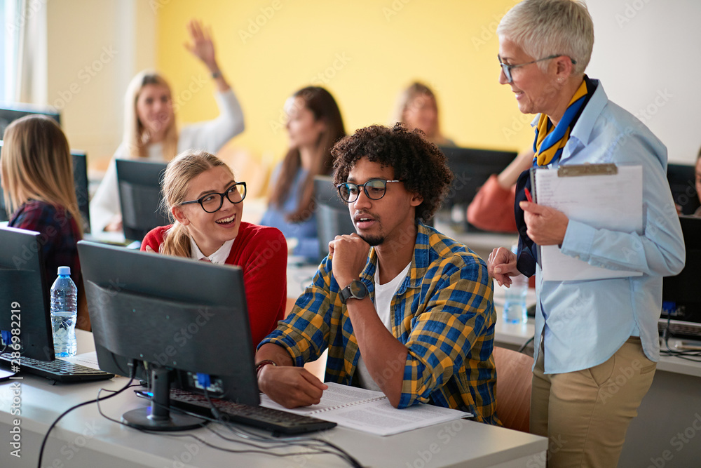 Woman lecturer in computer class assisting multi-ethnic student on ...