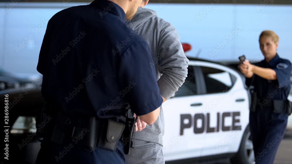 Police officers arresting dangerous criminal aiming gun, street crime ...