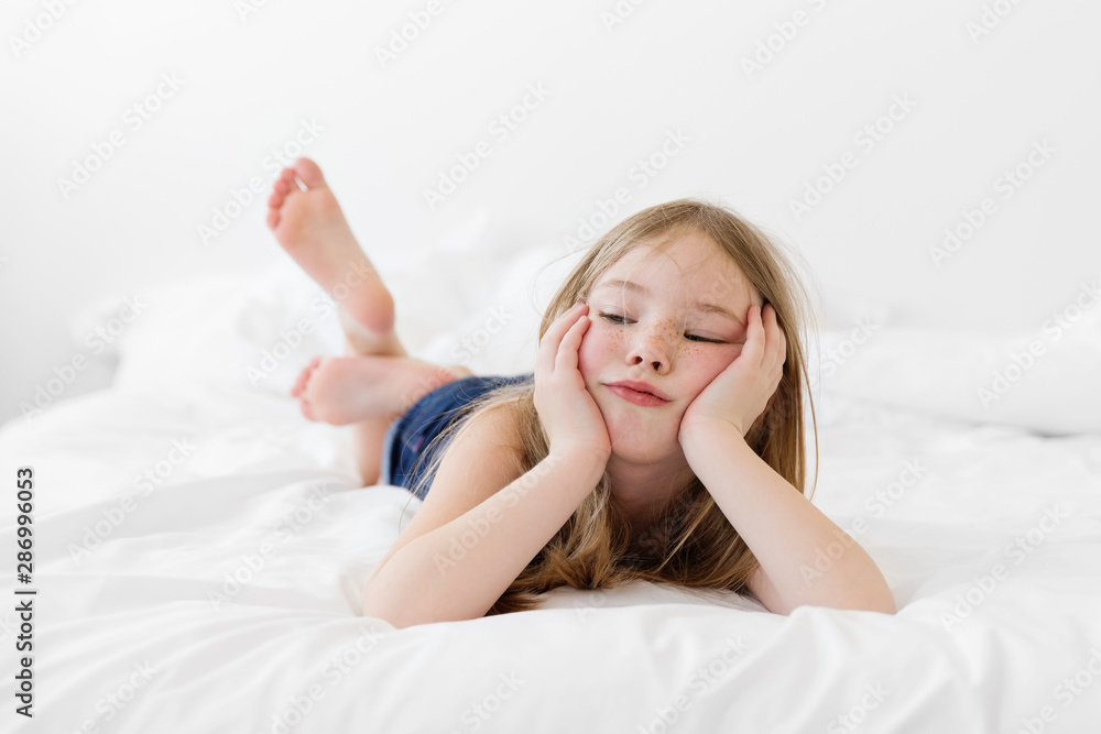 Young girl lying on bed with face in her hands looking bored Stock ...