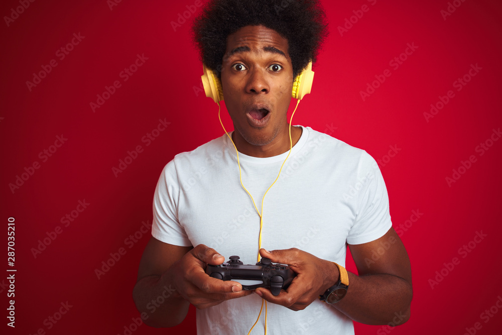 Afro gamer man playing video game using joystick headphones over ...