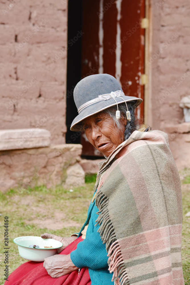 Native american old woman in traditional aymara clothes eating outside ...