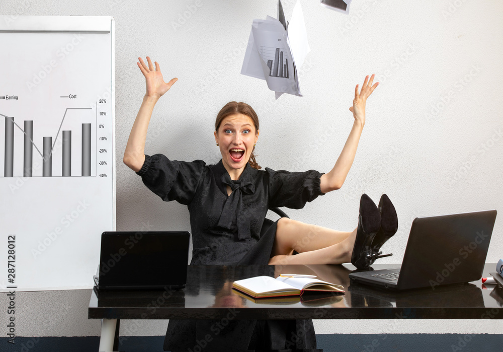 emotional woman at work. she's sitting at her desk with two laptops ...