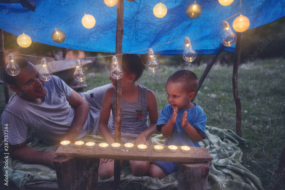Kids making a small tent with candles and lampions in the backyard ...
