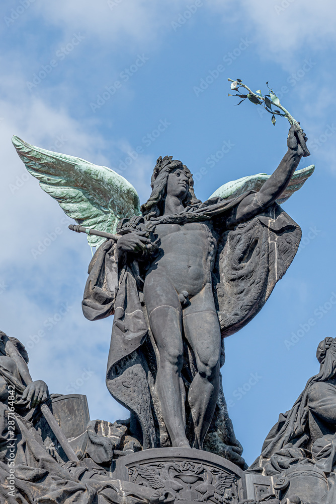 Old statue of a black angel as a warrior with green wings at the roof ...