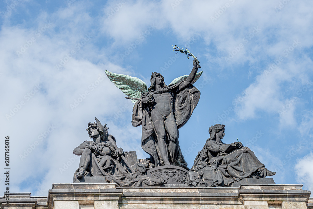 Old statue of a black angel as a warrior with green wings at the roof ...