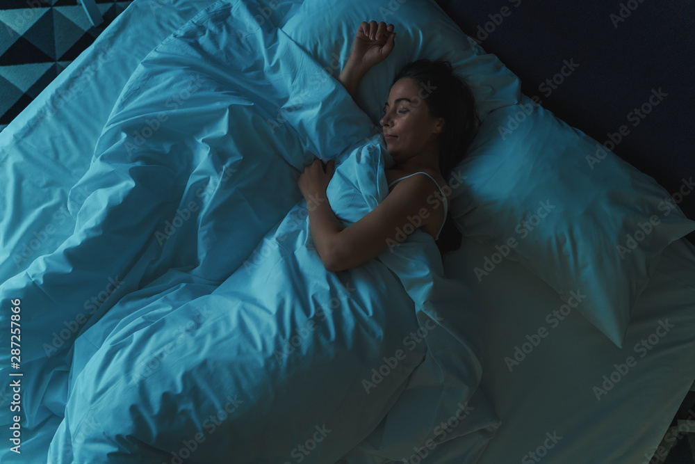 Young beautiful girl or woman sleeping alone in big bed at night, top ...