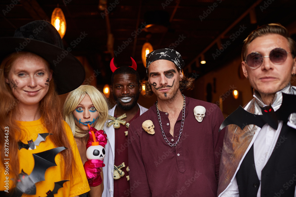 Multi-ethnic group of people wearing Halloween costumes posing looking ...