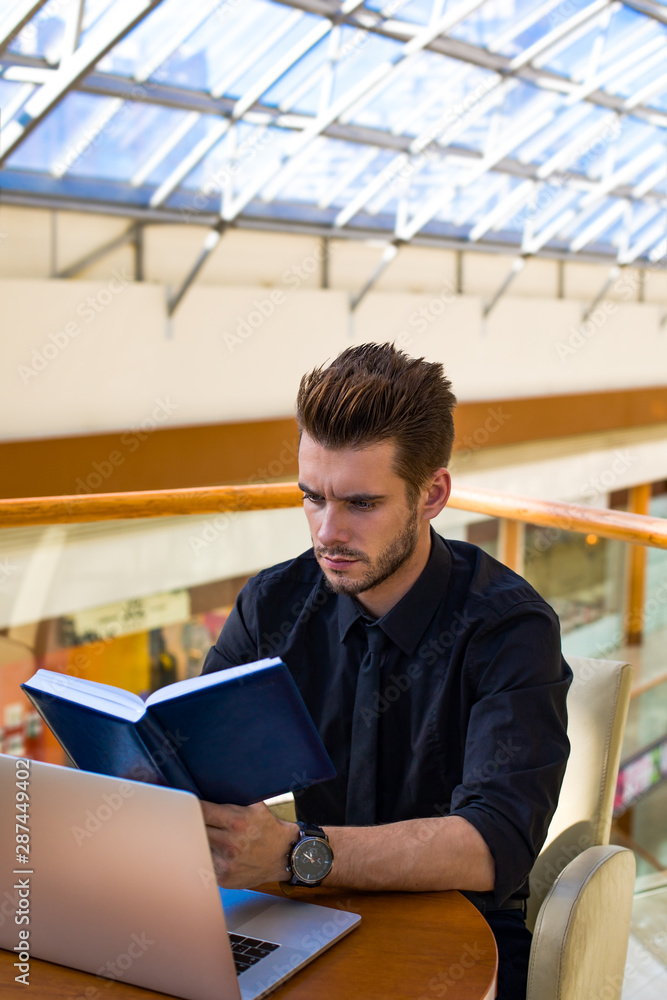 Young modern businessman reading information form textbook, sitting ta ...