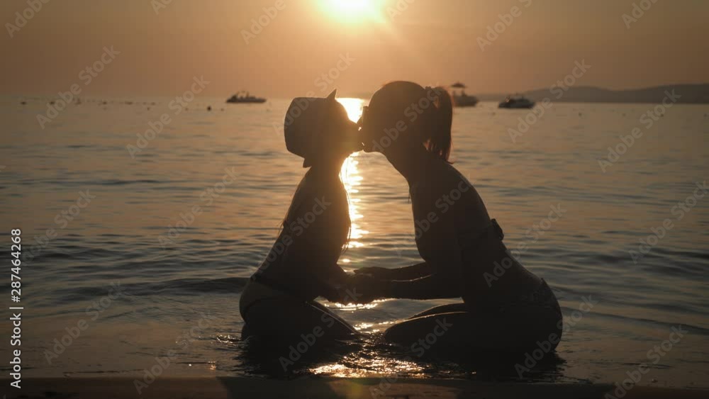 Silhouettes Mother And Daughter Sit On The Beach At Sunset Concept Of