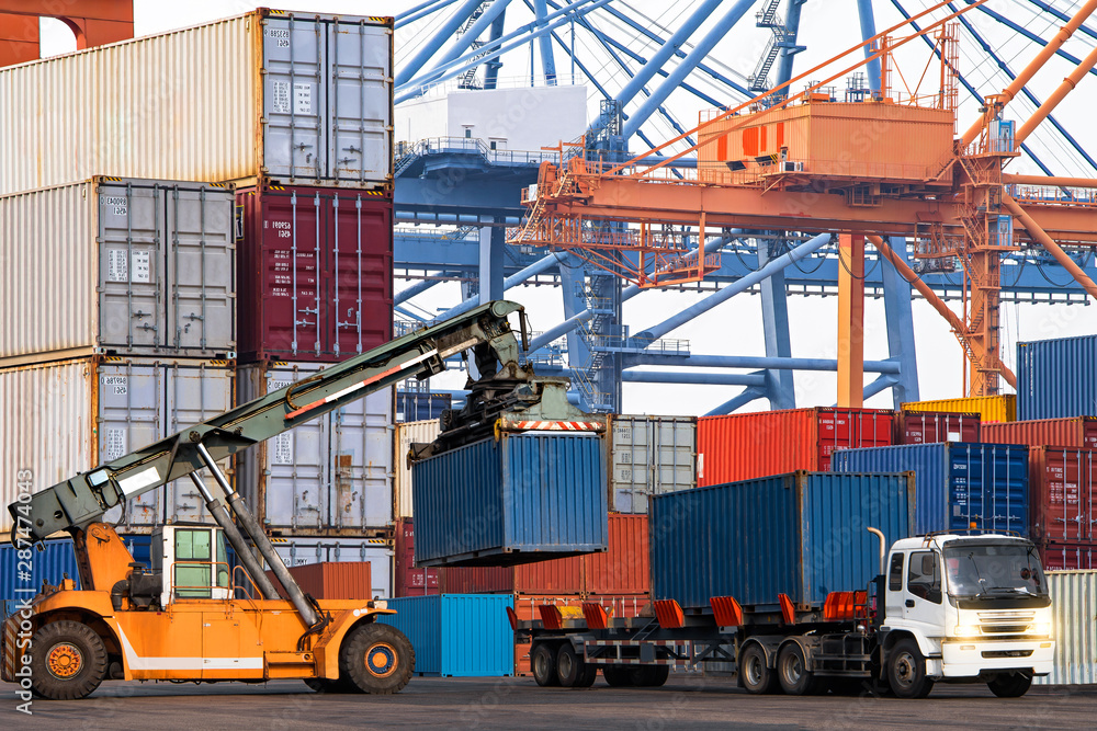 The cargo ship industry is parked in a harbor with a large crane bridge, transporting goods ...