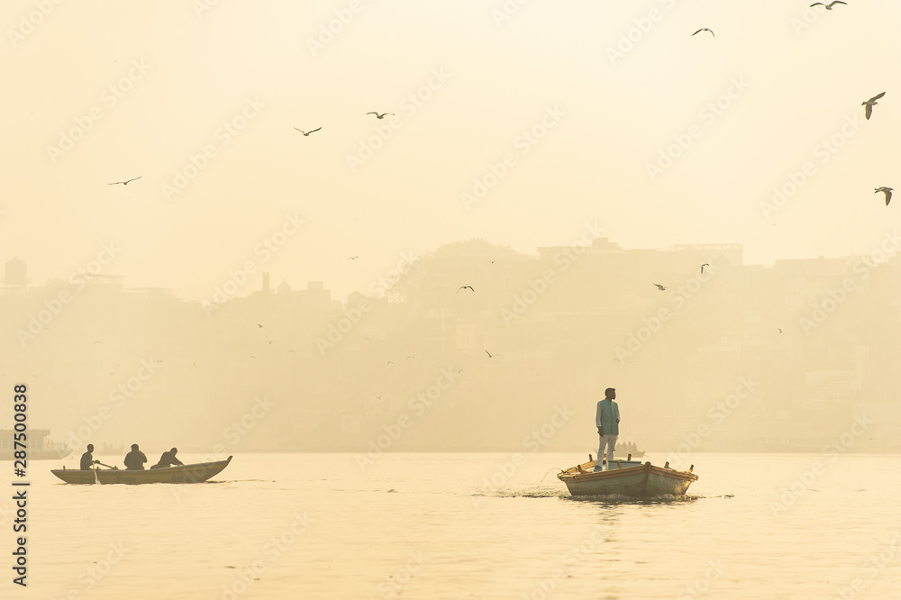 A man is sailing on his wooden boat in the sacred river Ganges in the ...