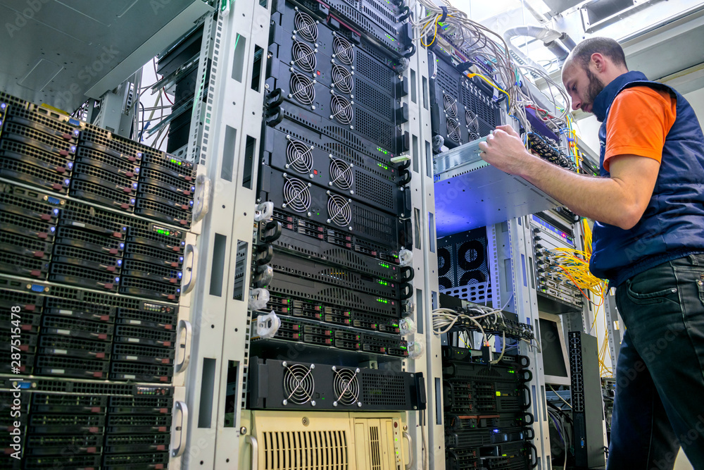 Technician repairs the central router. Man works in a server room ...