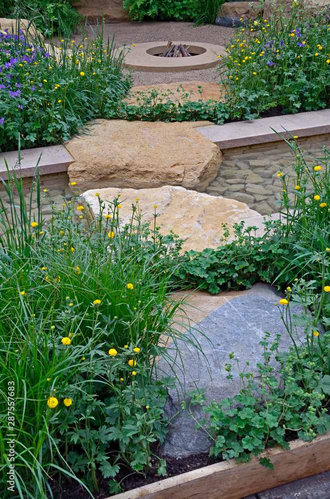 Modern water garden with flowing rill with rocks, stepping stones and ...