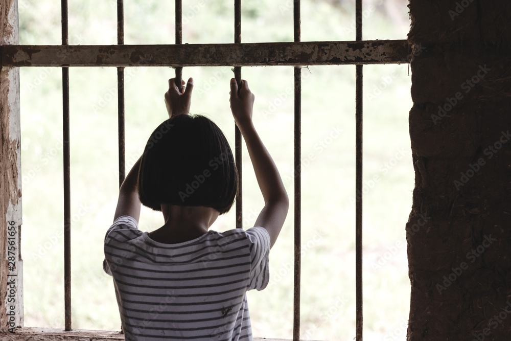 sad child holding a steel cage in old iron bar. children prison and ...