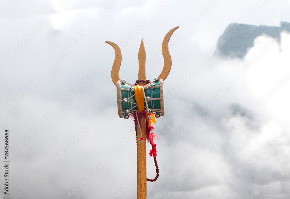 Trident weapon of lord shiva placed ahead of a cloudy mountain-image ...