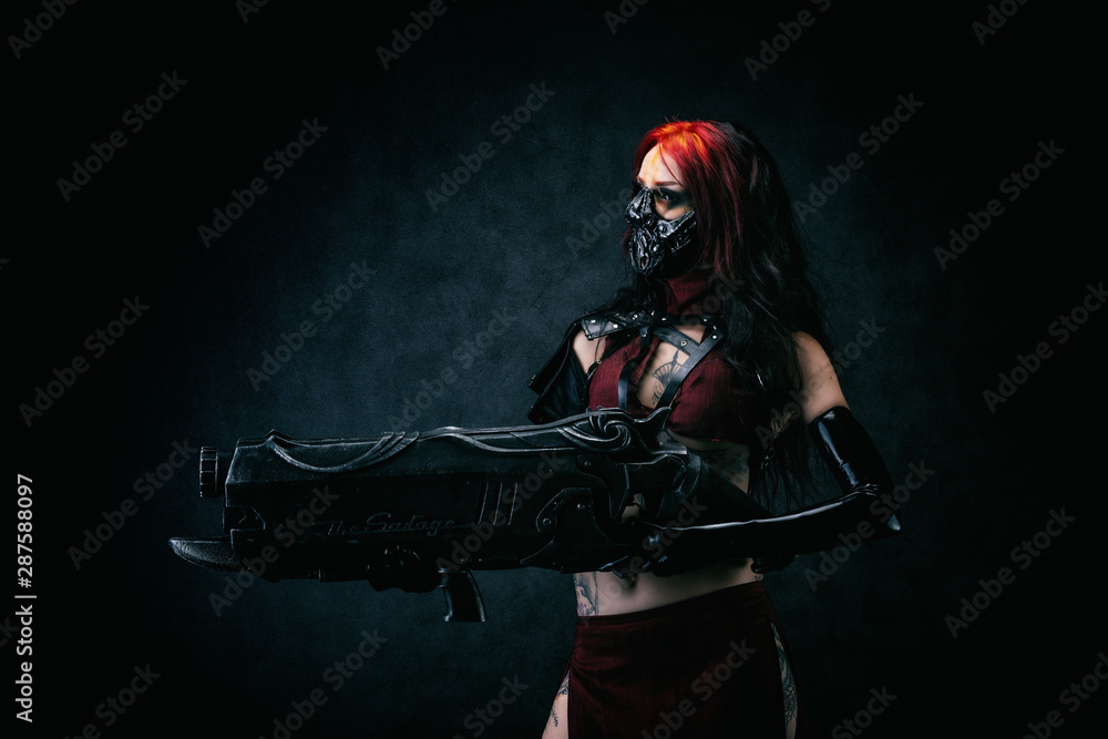 Young black-eyed Cyborg in leather armor holds a big futuristic weapon ...