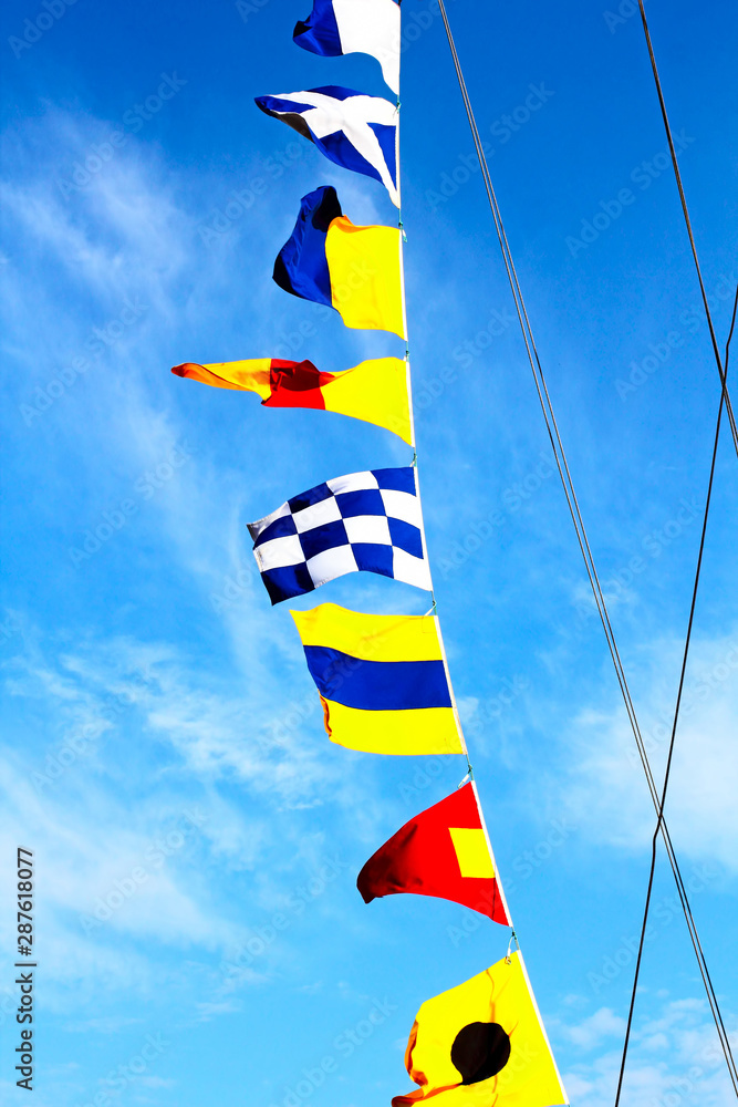 Marine signal flags set on a sailing mast against of the blue cloudy ...