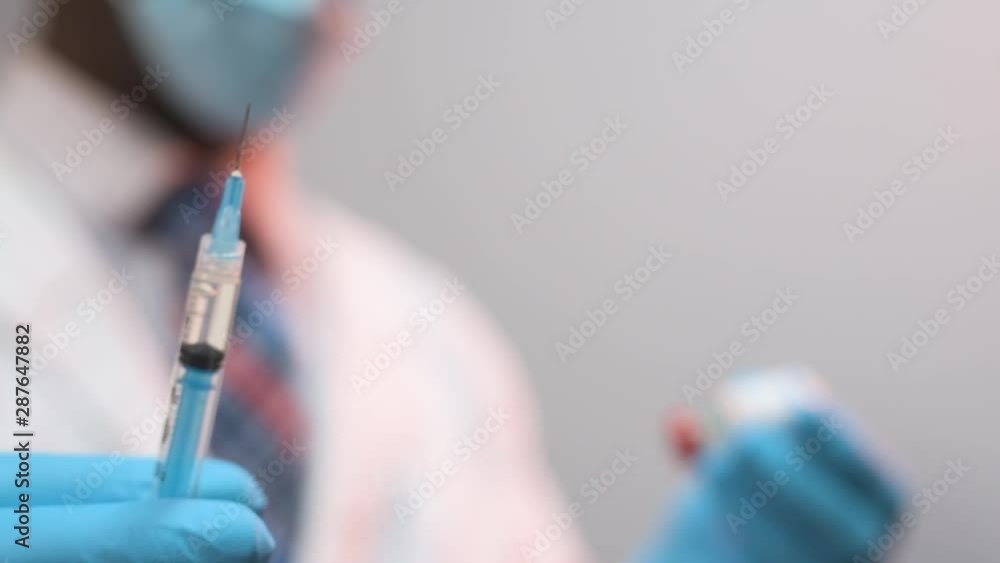 African American doctor drawing vaccine from vial into a syringe on a ...