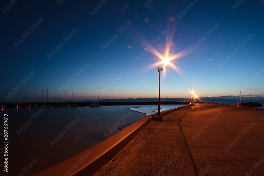 Harbor and light pole at marina dock at night, summer. Wide view. St ...