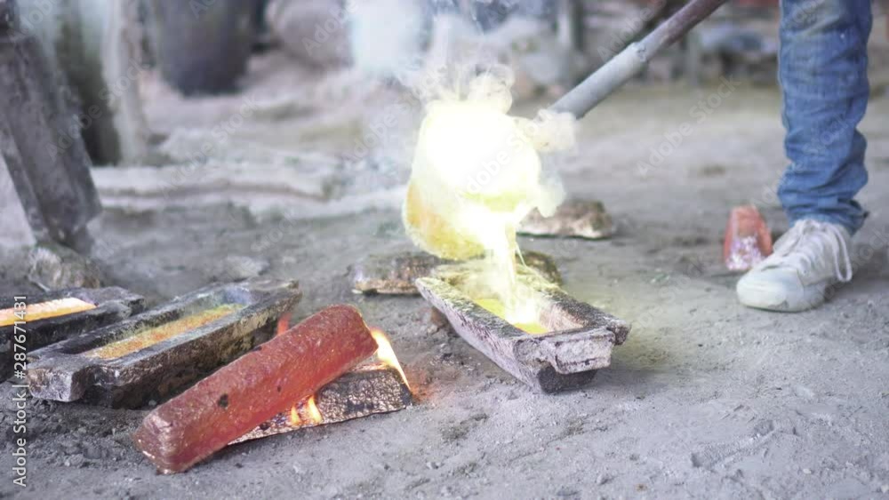 Artisan working gold melting process. Molted metal pouring into bar ...