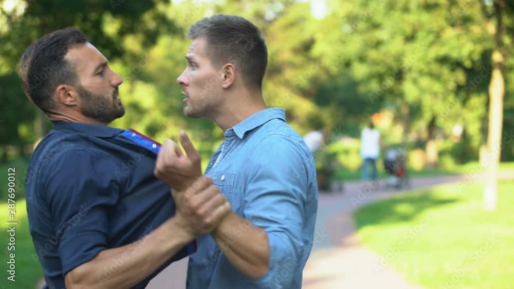 Angry men pushing and threatening each other outdoors solving problem ...