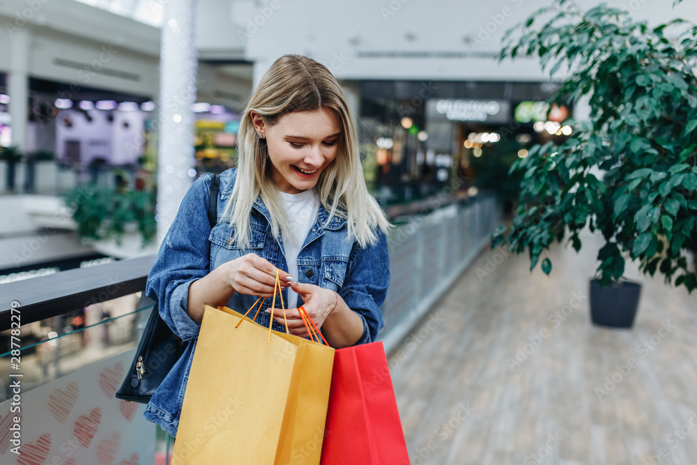 Shopping season. Beautiful laughing girl in a denim jacket with bags on ...